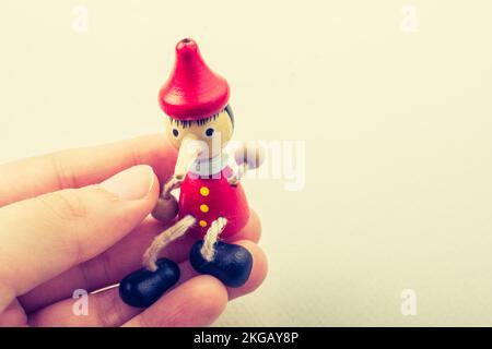 Wooden pinocchio doll in hand on a white background Stock Photo - Alamy
