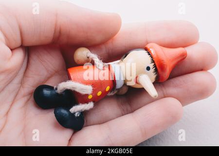 Wooden pinocchio doll in hand on a white background Stock Photo - Alamy