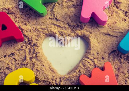 Heart shape and colorful Letters made of wood on sand Stock Photo - Alamy