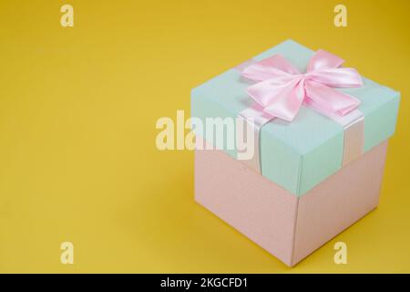Pink and cyan gift box with ribbon bow isolated on yellow background ...