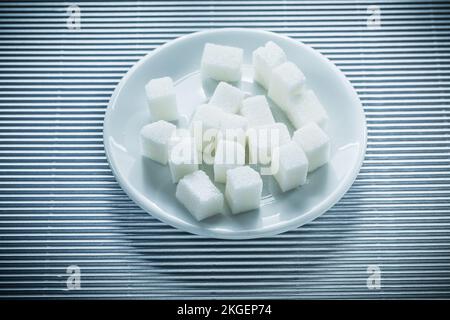 Saucer with sugar cubes on striped background Stock Photo - Alamy