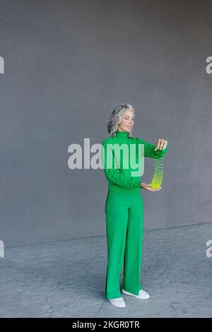 Woman stretching metal coil toy on footpath Stock Photo - Alamy