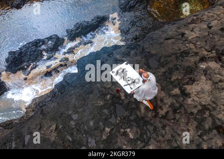 Monk doing calligraphy sitting on rock by sea Stock Photo - Alamy