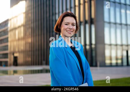 Businesswoman wearing blue blazer standing near office building Stock ...