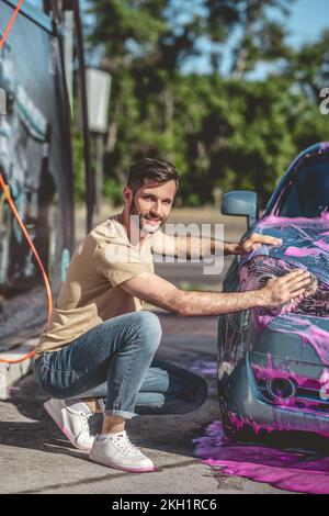 Experienced car detailer washing the motorcar headlight outdoors Stock ...