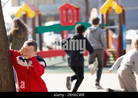 Boy playing hide and seek with friends Stock Photo - Alamy