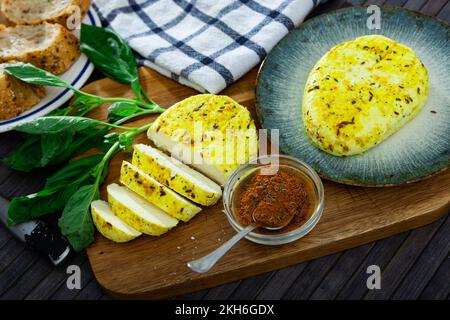 Sliced fried cottage cheese with cumin and turmeric on wooden board ...