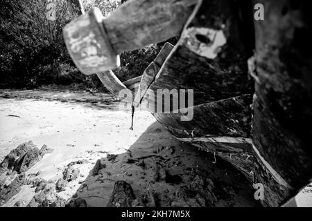 A grayscale shot of a wooden boat moored on the white beach in Zanzibar ...