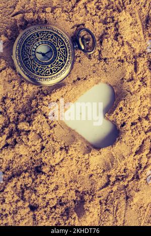 Retro style watch beside a heart shape made on sand Stock Photo - Alamy