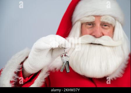 Santa Claus holds keys on a white background. New home gift for ...