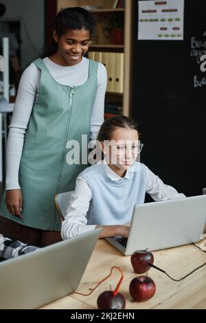 Caucasian elementary schoolgirls looking at digital tablet while ...