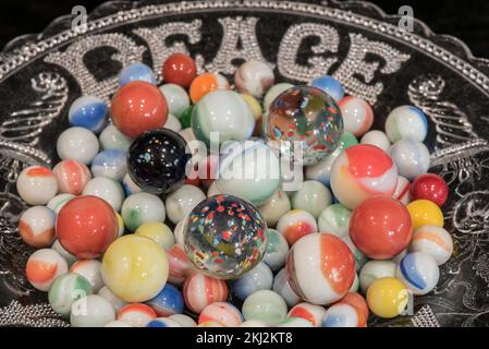 Colourful marbles on a glass 'Peace & Plenty' plate Stock Photo - Alamy