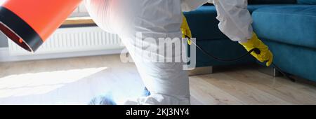 Person in hazmat suit disinfects living room with spray gun Stock Photo ...