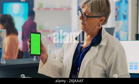 Pharmacy worker showing smartphone with greenscreen display, holding ...