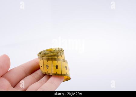 Hand holding a yellow color measuring tape on a white background Stock ...
