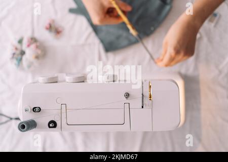 Lady cuts a thread from a sewing machine with scissors Stock Photo - Alamy