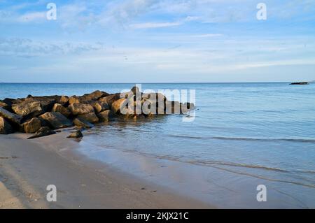Stone groyne jutting into sea in Denmark with clouds in sky. Coastal ...