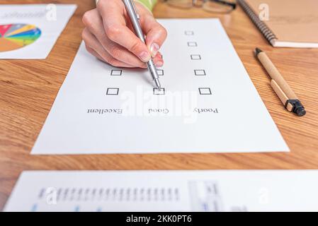A woman's hand fills out a checklist or an exam test giving a mark of ...