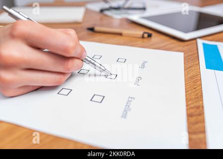 A woman's hand fills out a checklist or an exam test giving a mark of ...