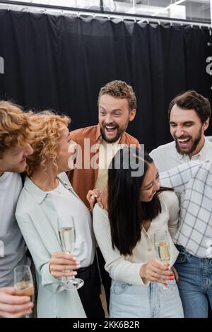 Interracial business people holding glasses of champagne near balloons ...