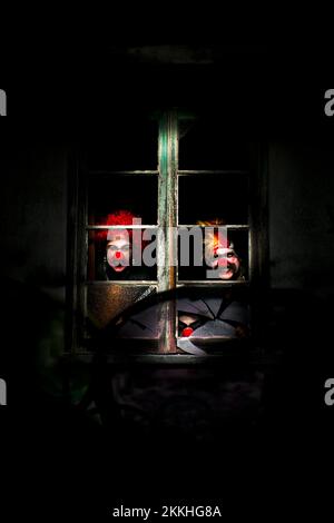 a scary evil clown peering out from a purple stage curtain, with his ...