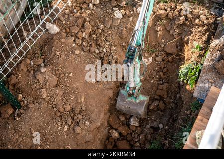 Mini excavator digs a trench to lay pipes. Close up of an excavator ...