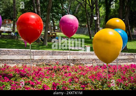 Color baloons are placed in a park by the flowers Stock Photo - Alamy