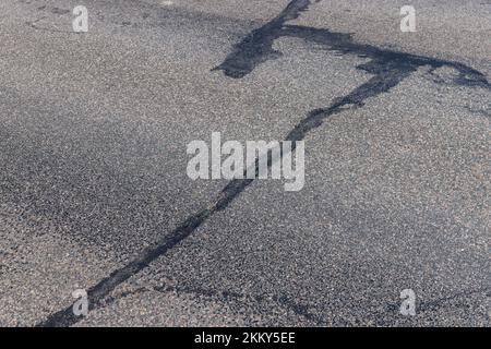 Repaired asphalt road in close up, paved road with traces of repair and ...