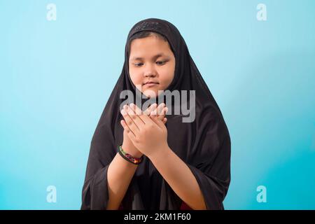 A religious Asian Muslim child girl in the Muslim hijab dress is ...