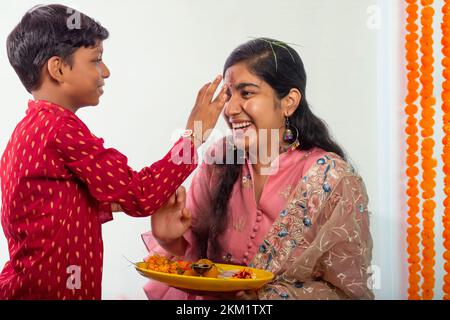 Brother applying tika on his sister's forehead on the occasion of ...