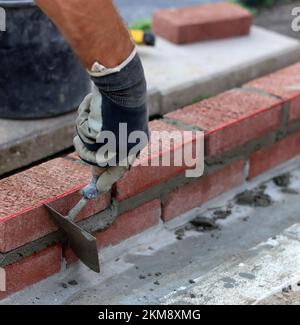 Construction work in progress. Male builder working with red bricks ...