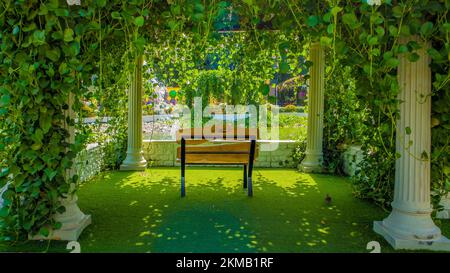 A single bench facing backwards inside an outdoor structure in a park ...