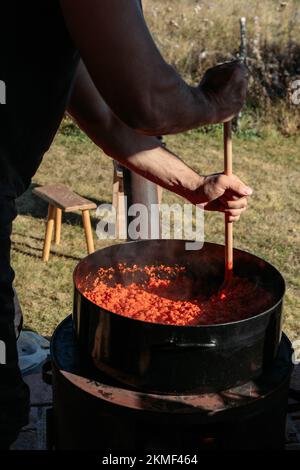 Male hand stirring ajvar in a big pot. Ajvar, traditional meal ...