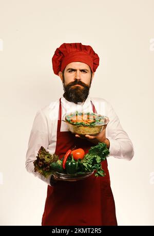 Chef holds bowl with potato casserole and parsley. Man with beard ...