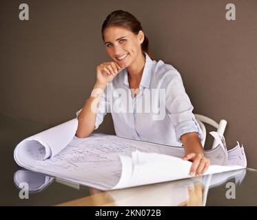 Lovely young woman architect sitting at the desk with house model ...