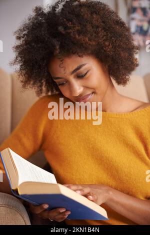 Engrossed in her novel. A young woman relaxing on a window sill and ...