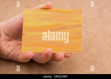 Hand holding painted note paper on brown background Stock Photo - Alamy