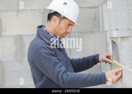 worker checks erected brick wall with level Stock Photo - Alamy