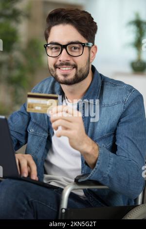 disabled person holds credit card and uses a pc Stock Photo - Alamy