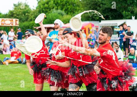 Team of four people in fancy dress throwing custard pies at another ...