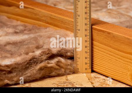 Measuring fiberglass insulation in attic of house with ruler. Home ...