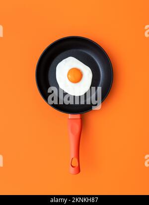 Single vibrant orange egg yolk centered in white ceramic bowl with blue ...