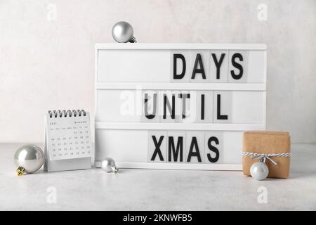 Board with text DAYS UNTIL XMAS, calendar, Christmas balls and gift on ...