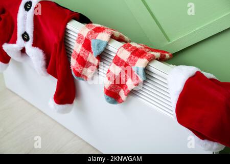 Baby Santa costume, socks and hat drying on electric radiator near ...