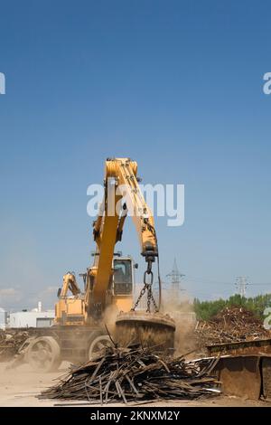 Material handler fitted with a magnet used to move a pile of ferous ...