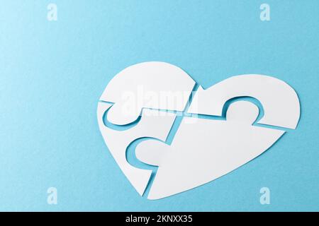 Composition of white heart made of jigsaw puzzle pieces on blue ...