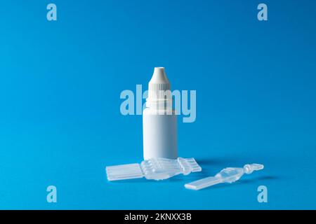 Composition of saline solution caplets and dropper bottle on blue ...