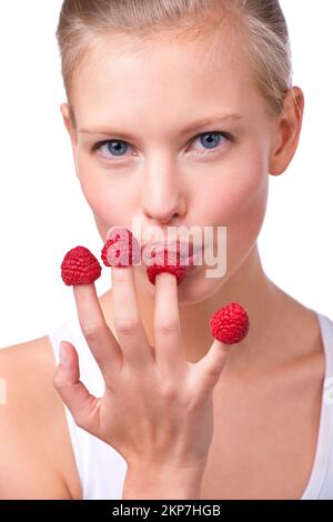 Berry playful. a beautiful young woman playfully eating raspberries off ...