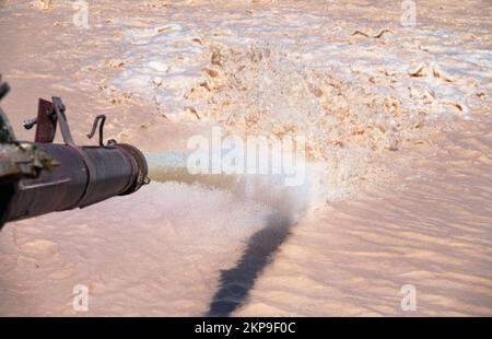 Foamy muddy water gushes out of the pipe under high pressure. Discharge ...