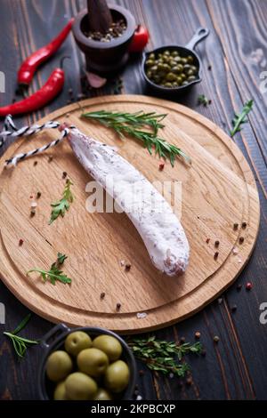 Spanish fuet salami sausageon wooden cutting board at domestic kitchen ...